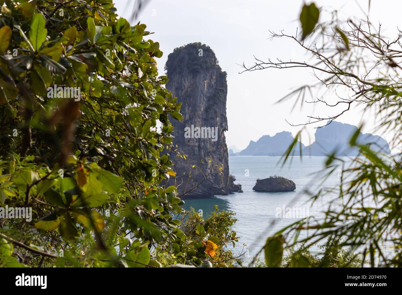 View of a rock in the azure sea through tropical trees Stock Photo - Alamy