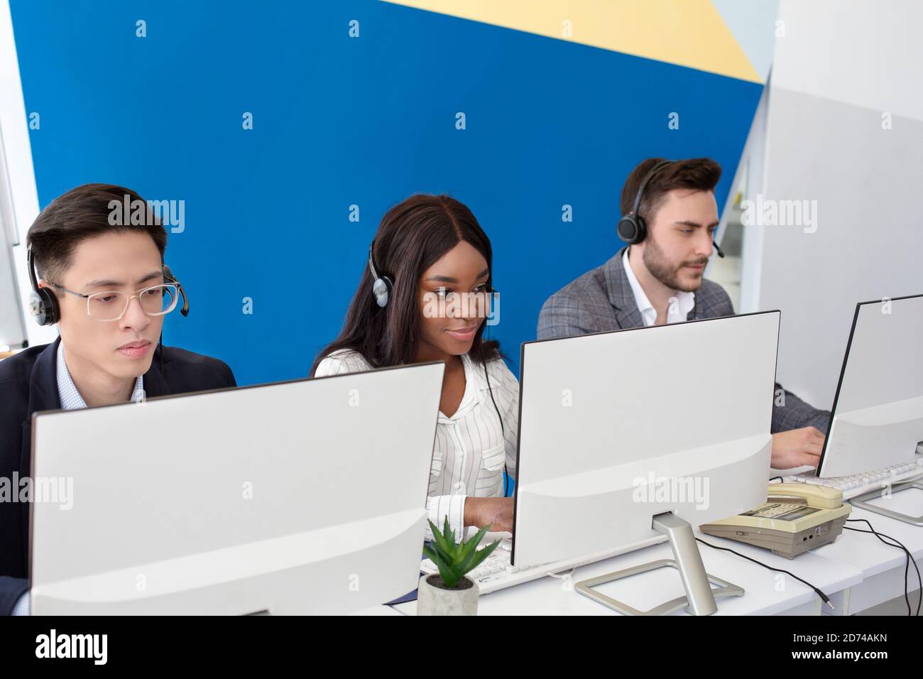Focused call center operators with headsets working in front of ...