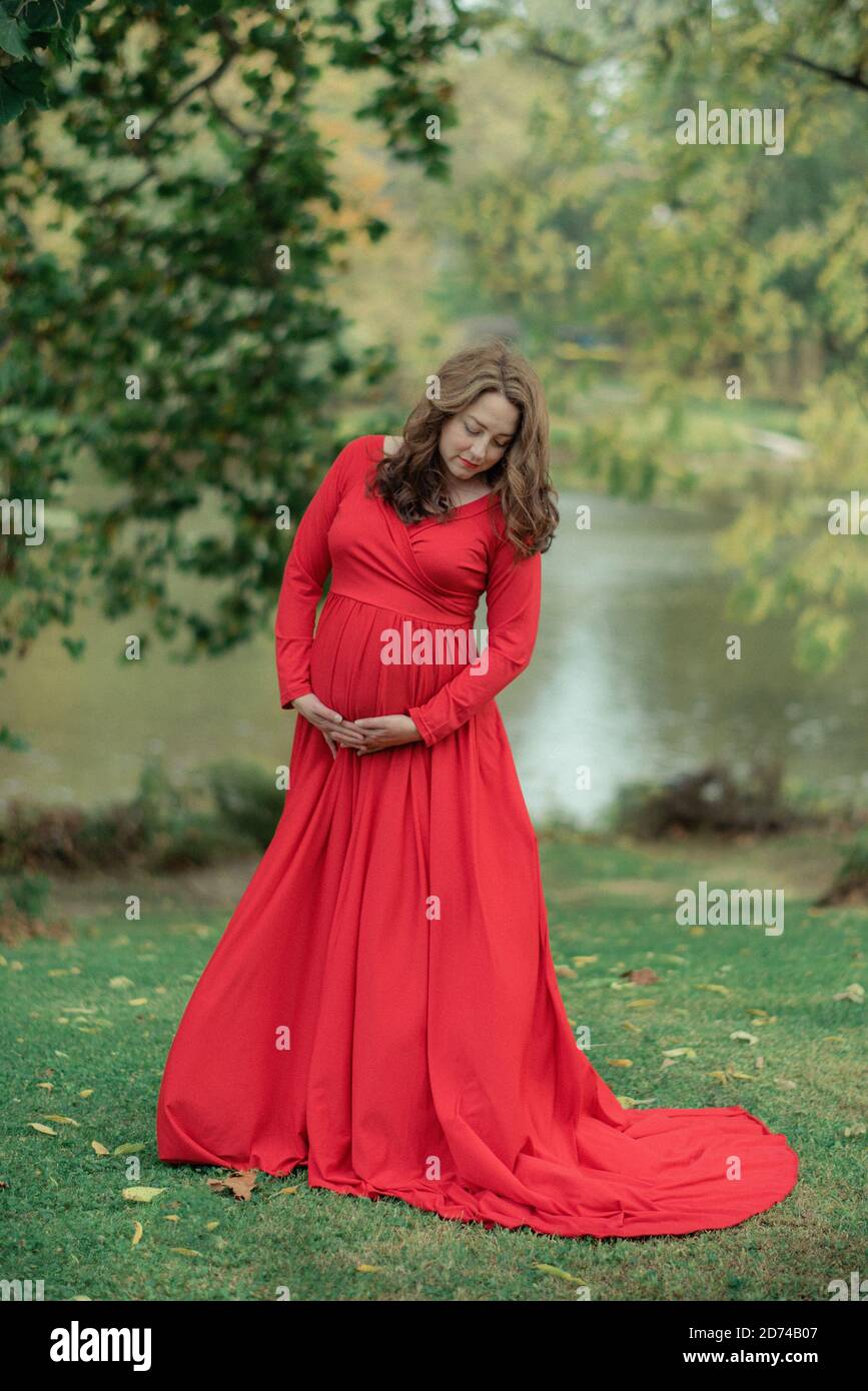 Woman in a red dress for maternity photos Stock Photo - Alamy