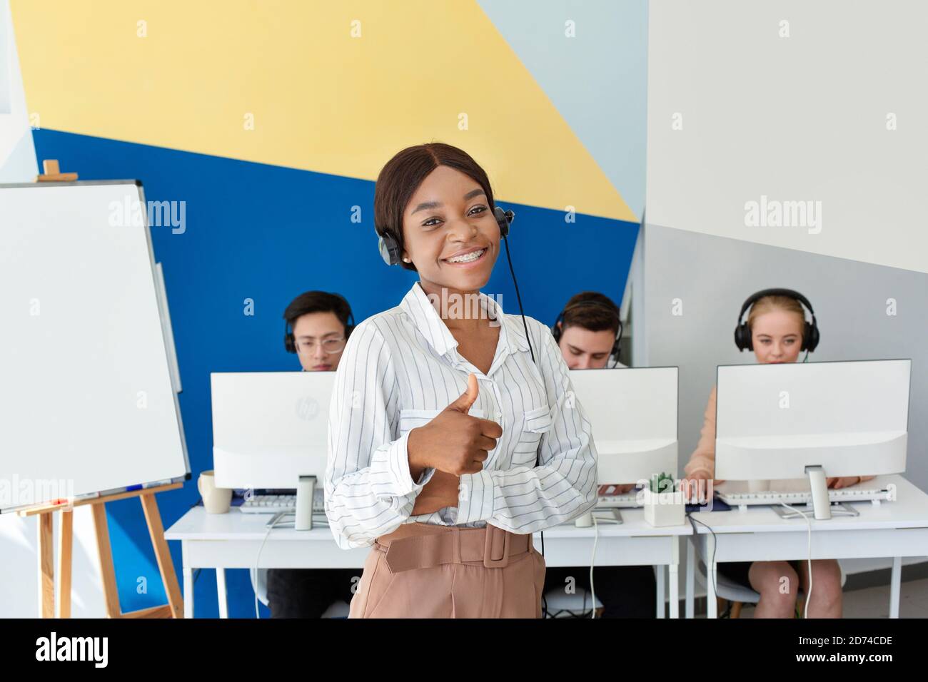 Black female hotline operator smiling and showing thumb up at modern ...