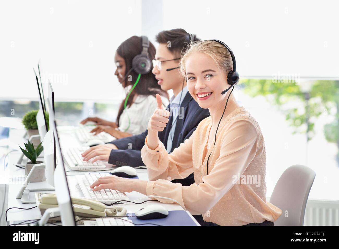 Happy female call centre consultant showing thumb up gesture and her ...