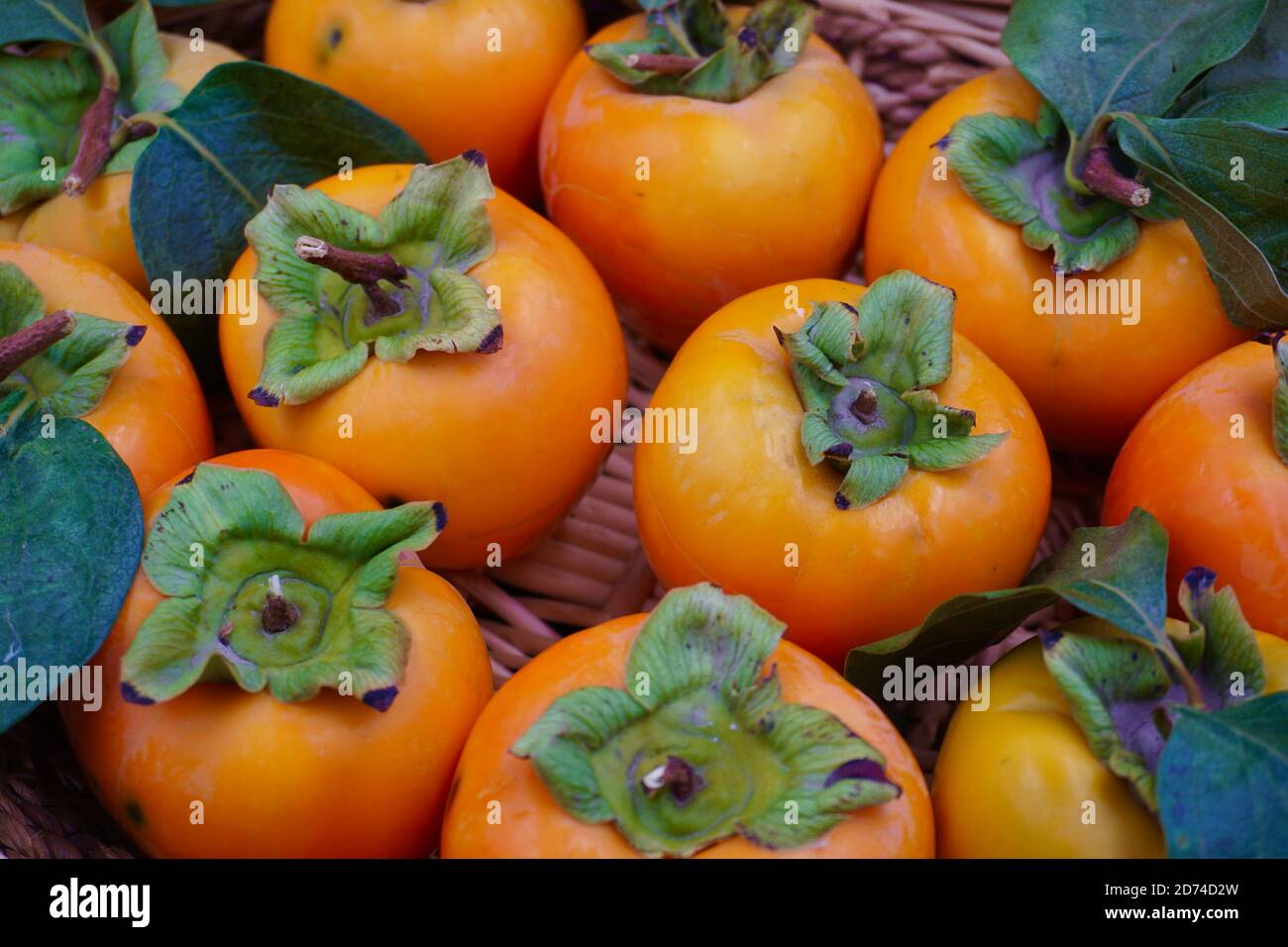 Persimmon pears (Diospyros) (kaki) in a wicker basket Stock Photo - Alamy