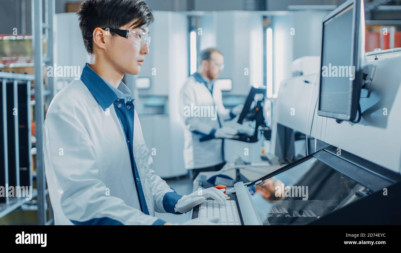 On High Tech Factory Asian Engineer Uses Computer for Programing Pick ...