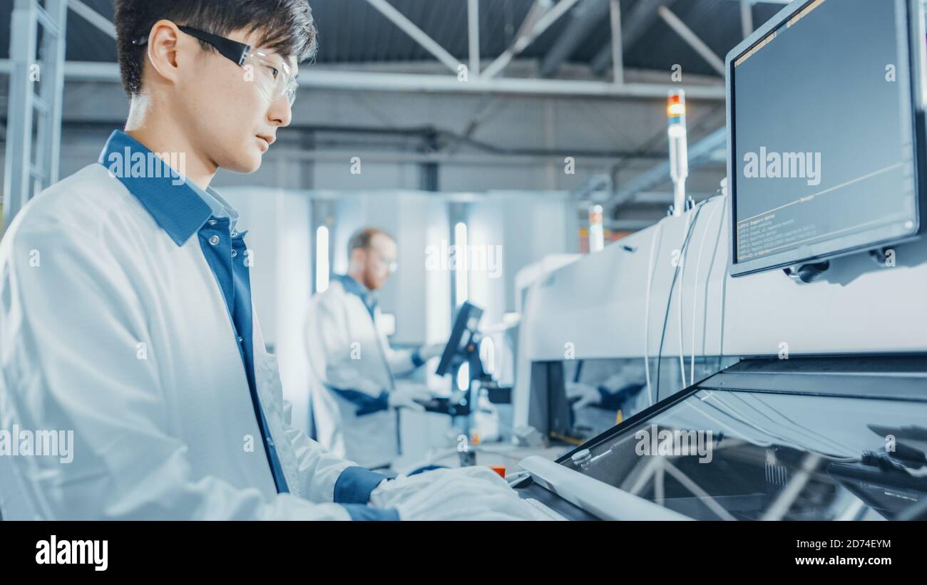 On High Tech Factory Asian Engineer Uses Computer for Programing Pick ...