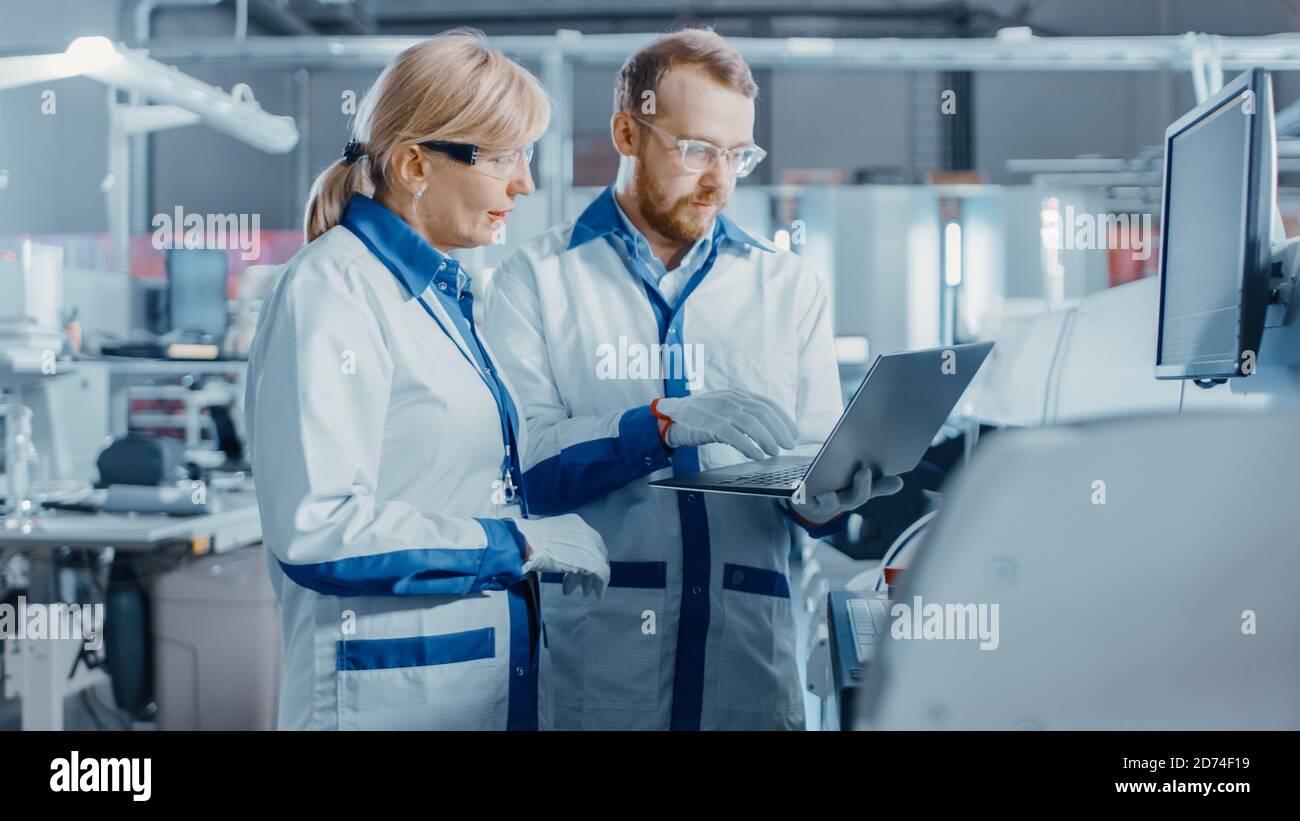On High Tech Factory Female and Male Engineers Talk and Use Computer ...