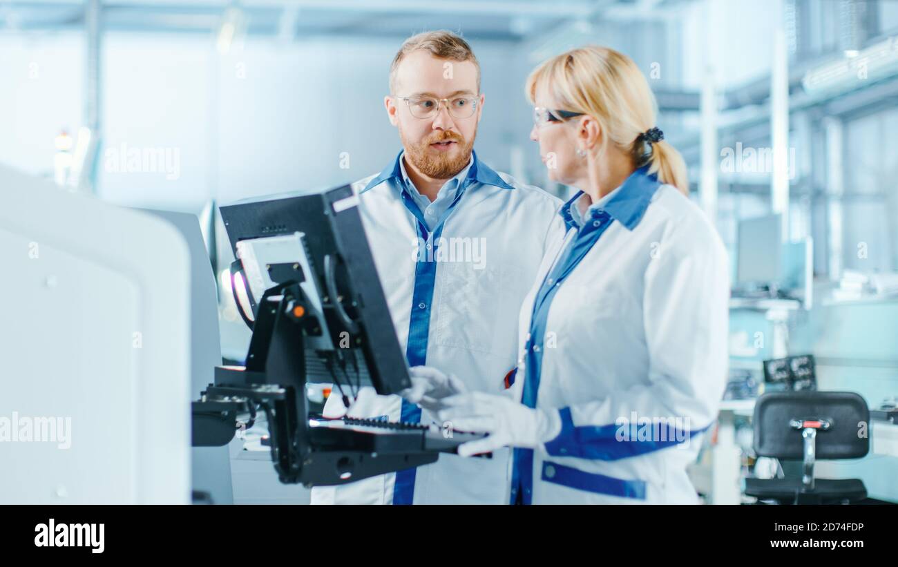 On High Tech Factory Female and Male Engineers Talk and Use Computer ...