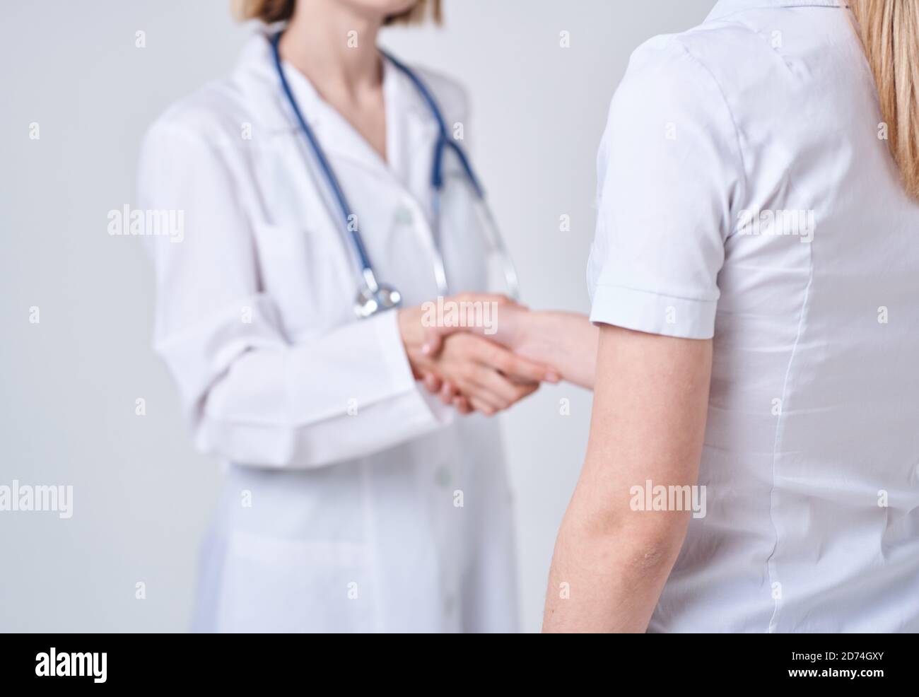 Doctor and patient shake hands with each other on a light background ...