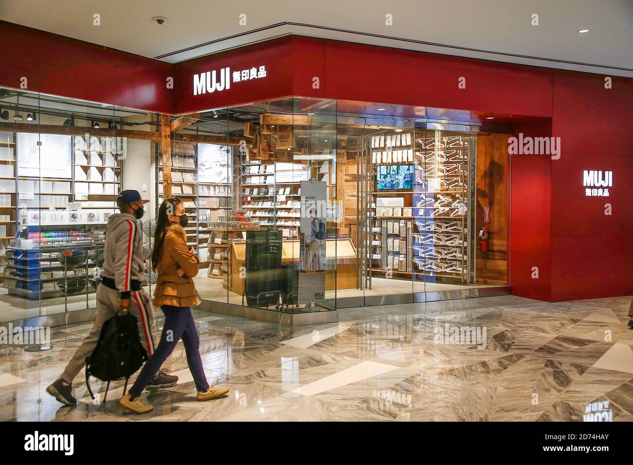 People wearing face masks walk past the Muji store in Hudson Yards ...