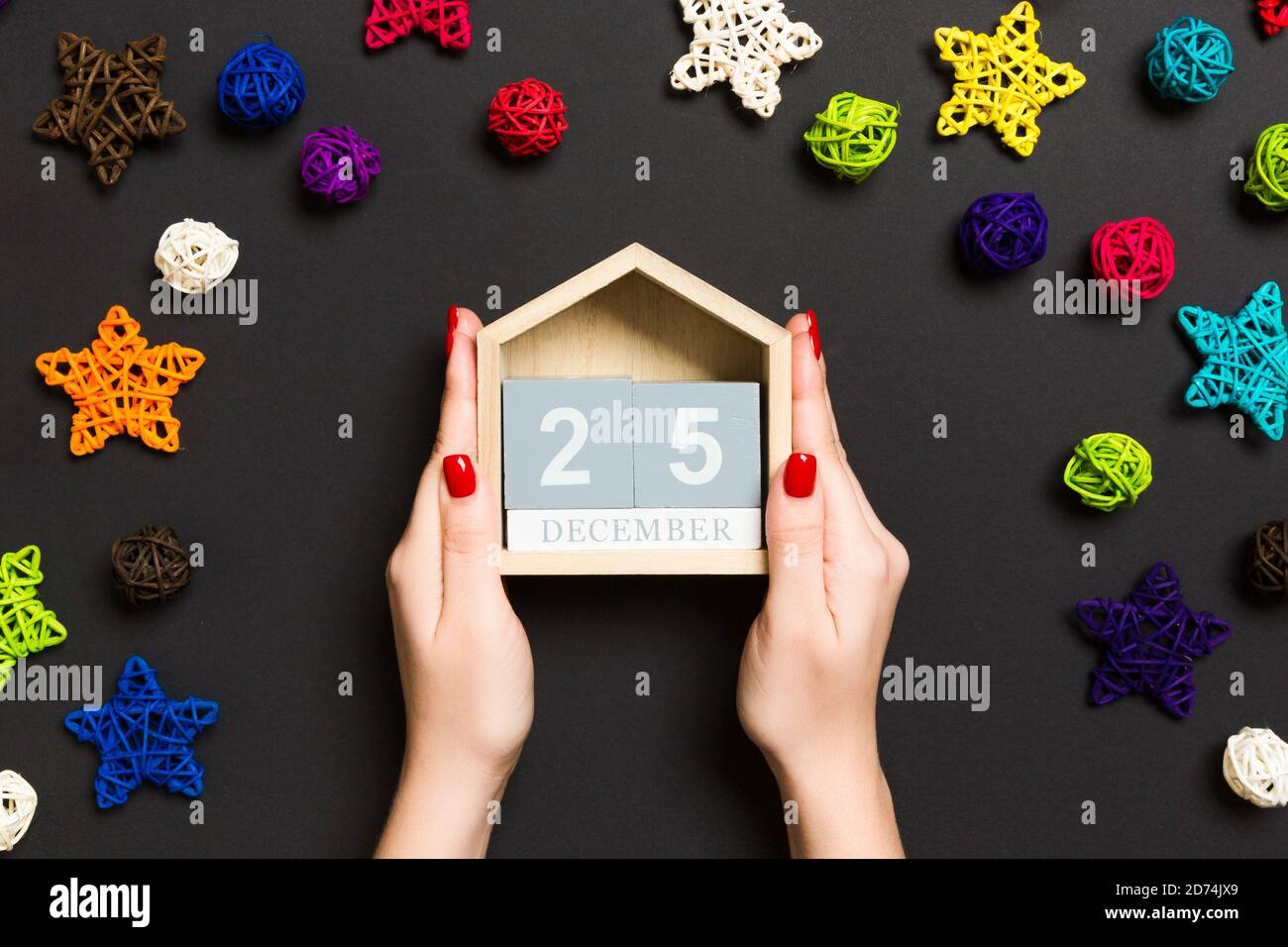 Top view of female hands holding calendar on black background. The ...