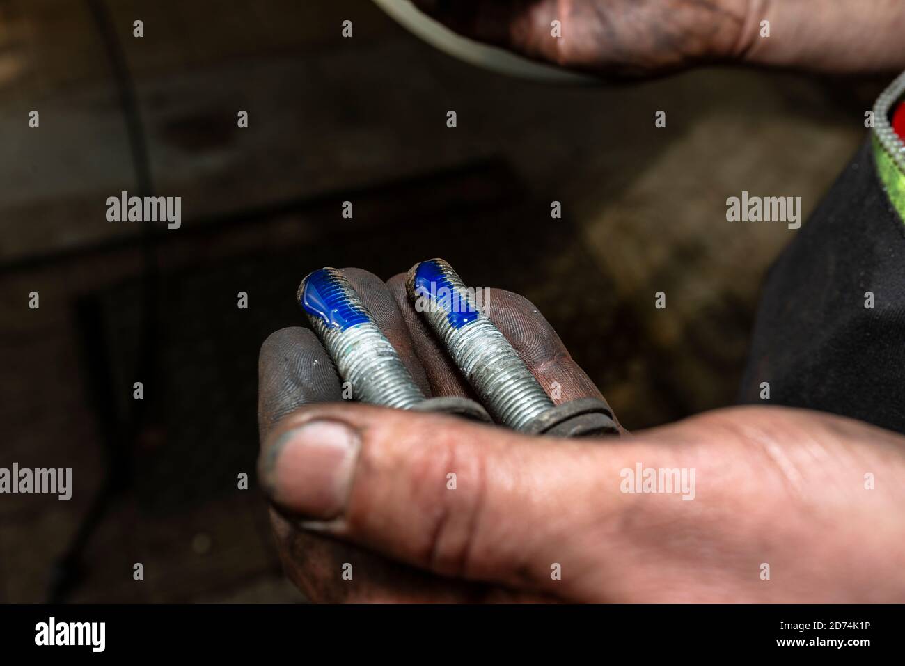 Car mechanic applies a layer of blue thread glue to the screw in his ...