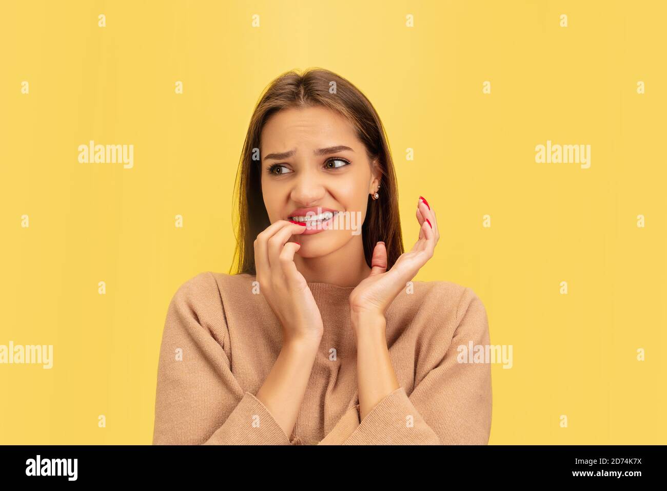 Scared, shy. Portrait of young caucasian woman isolated on yellow ...