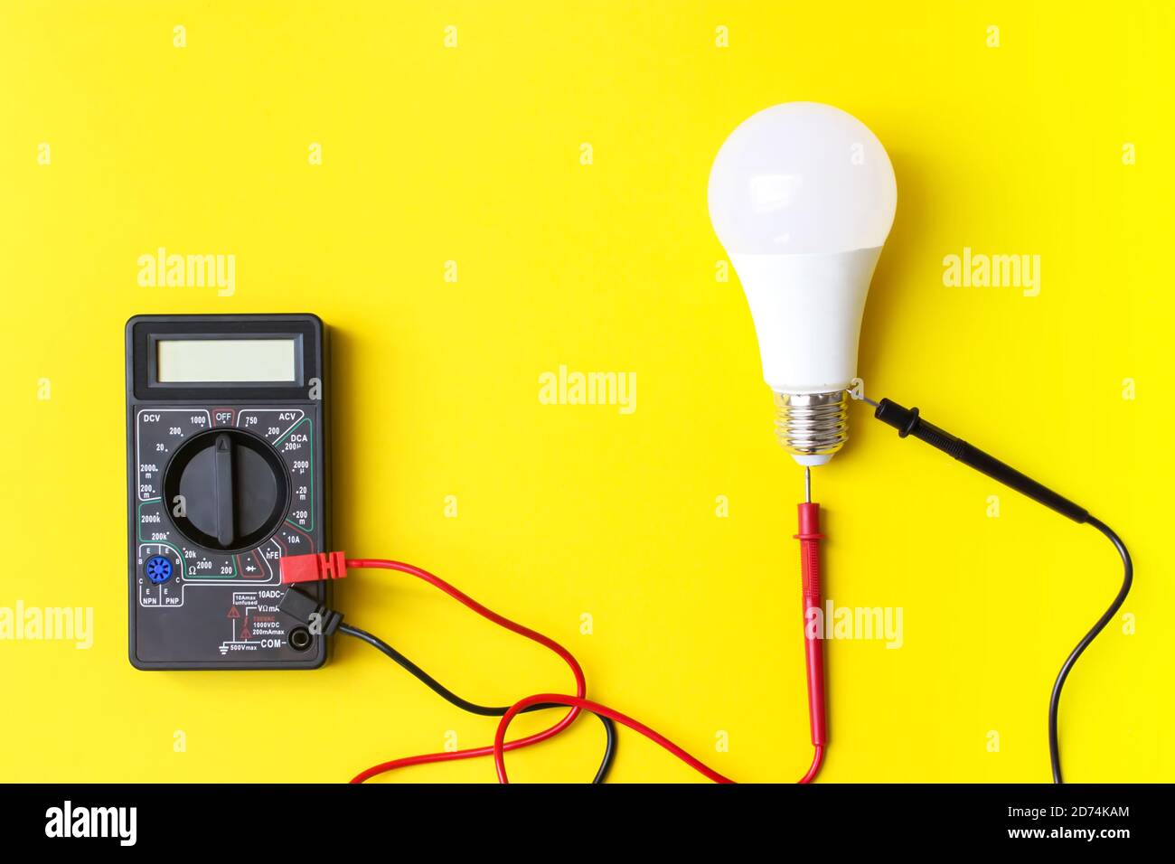 White glowing light bulb Dark Digital multimeter with probes. Power ...