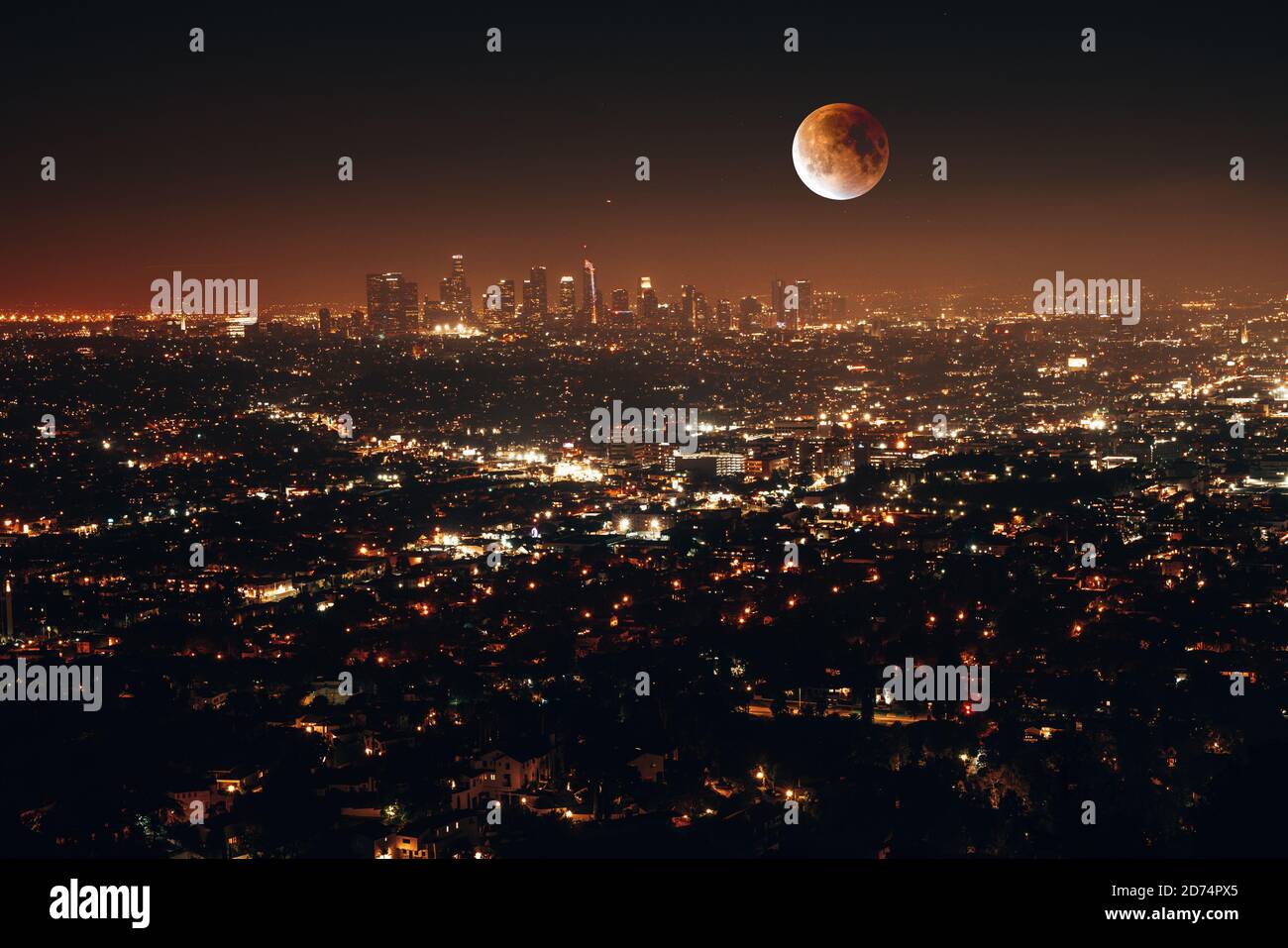 Night aerial view of city lights surrounded by buildings with a full ...