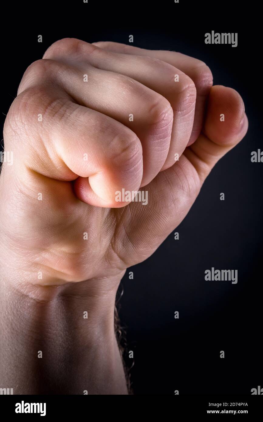Aggressive gesture. Hand compressed in fist. Photo against dark ...