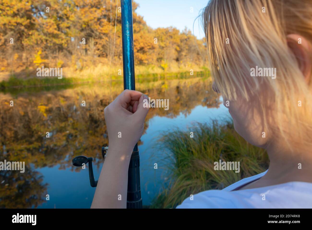 Young woman fisherman holds fishing rod hook with live bait. Fishing ...