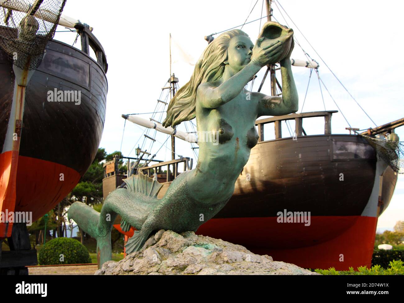 Bronze mermaid sculpture with long flowing hair blowing into a conch ...