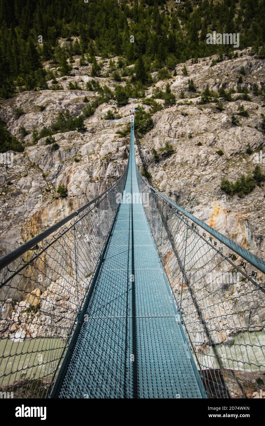 Wooden long footbridge above the deep gorge with a river beach at the ...