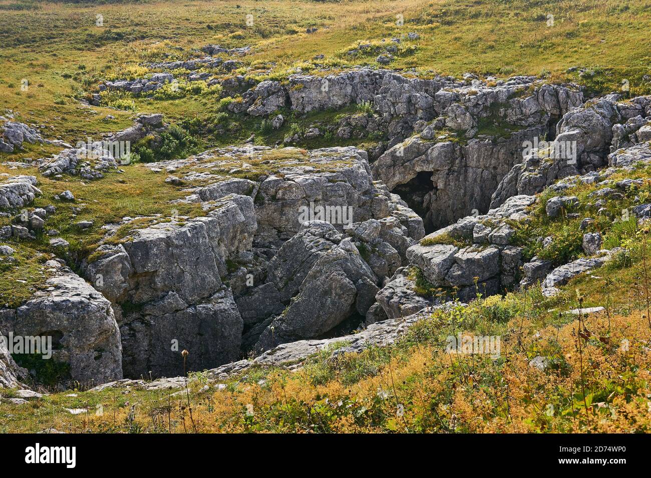 karst sinkhole with steep rocky walls in the middle of an autumn alpine ...