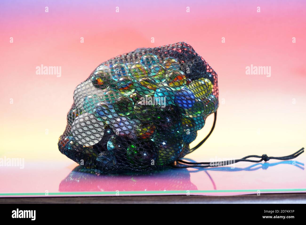 Closeup of a squishy mesh ball on a reflecting surface with a pink ...