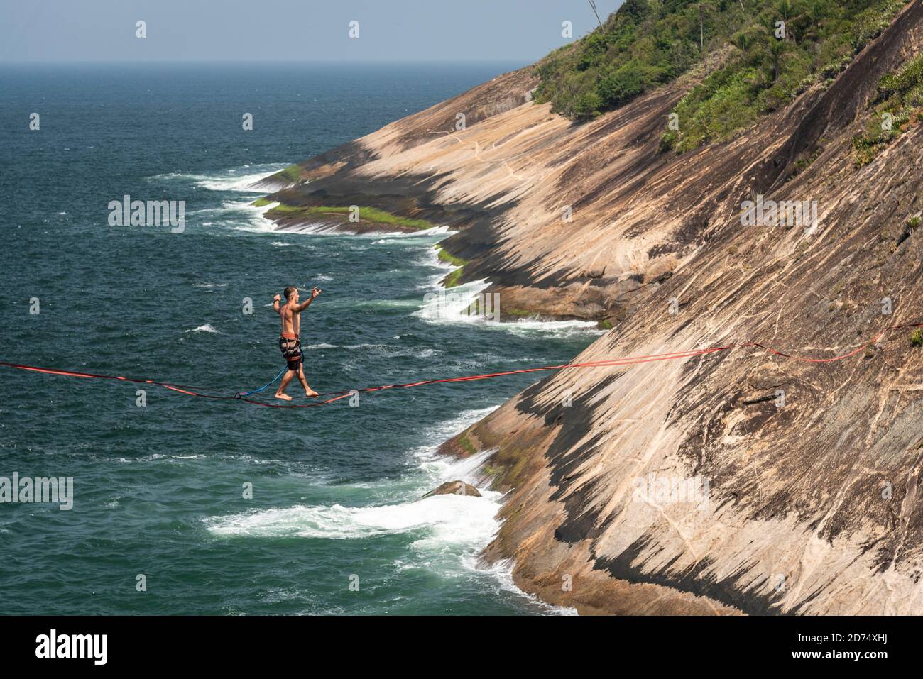 Beautiful view to highliner walking the line on rocky ocean front ...