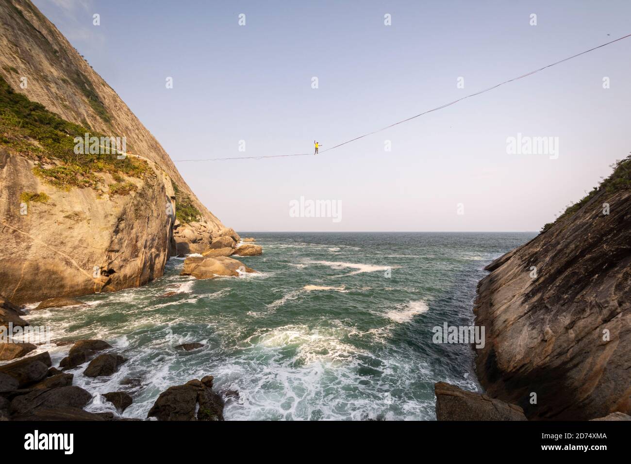 Beautiful view to highliner walking the line on rocky ocean front ...