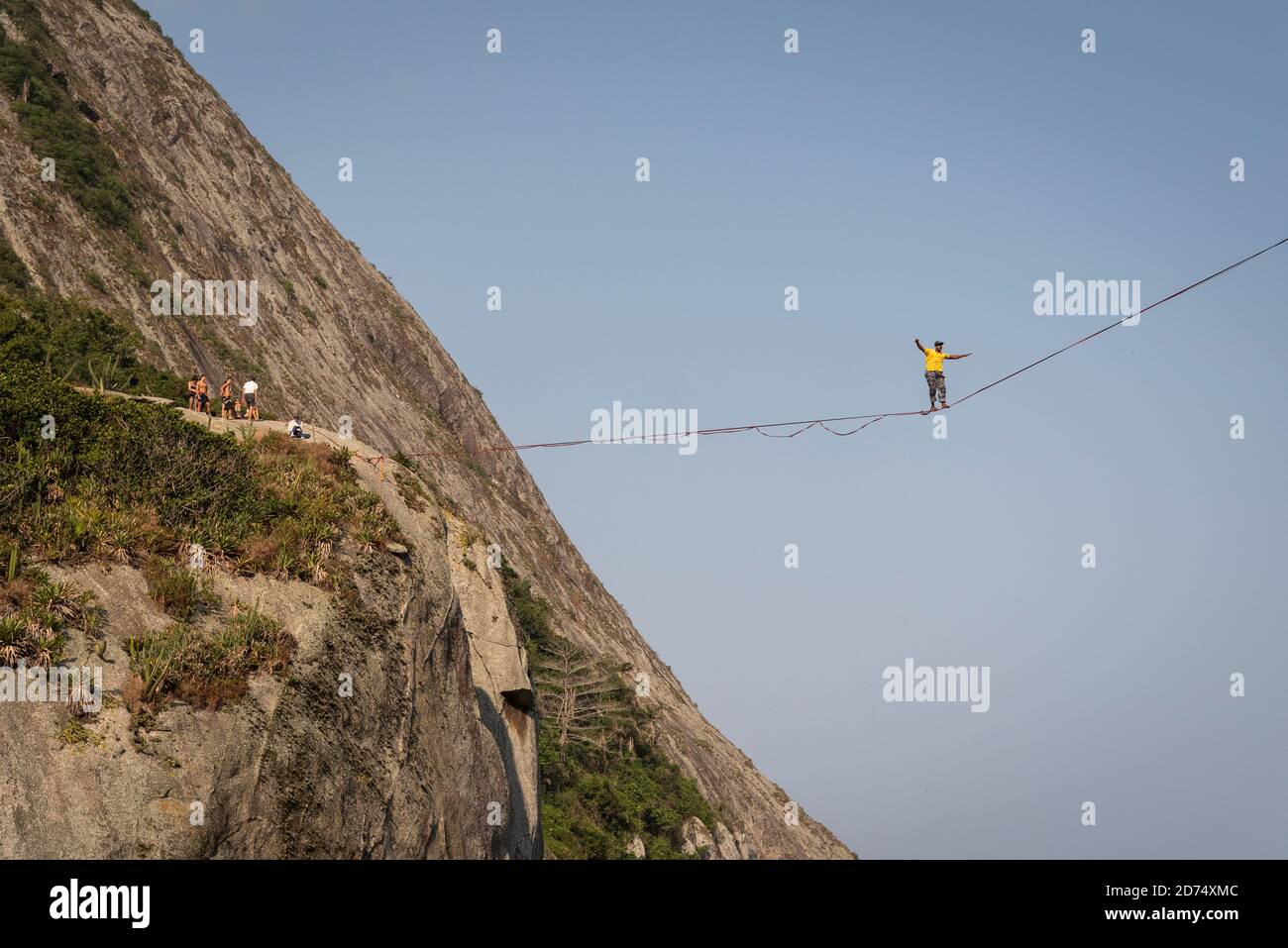 Beautiful view to highliner walking the line on rocky ocean front ...