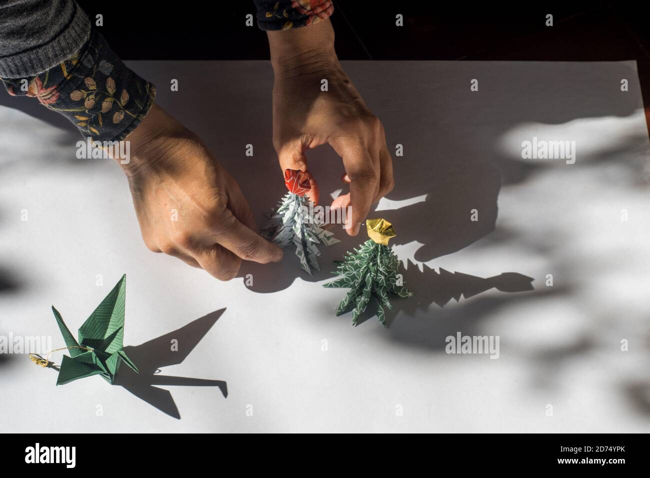 Hands making arrangement of Christmas decorations, handmade with paper ...
