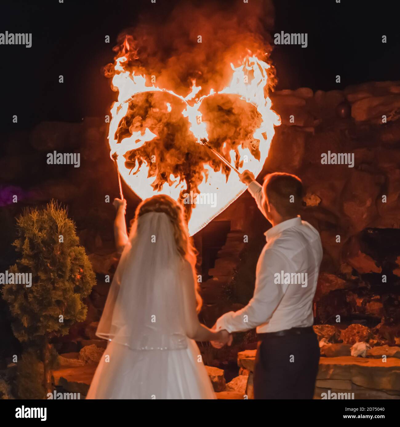 The groom and bride light a heart-shaped fire Stock Photo - Alamy