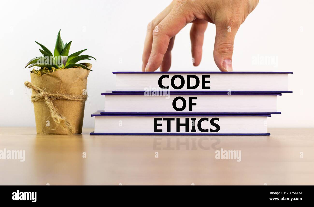 Books with text 'code of ethics' on beautiful wooden table, white ...