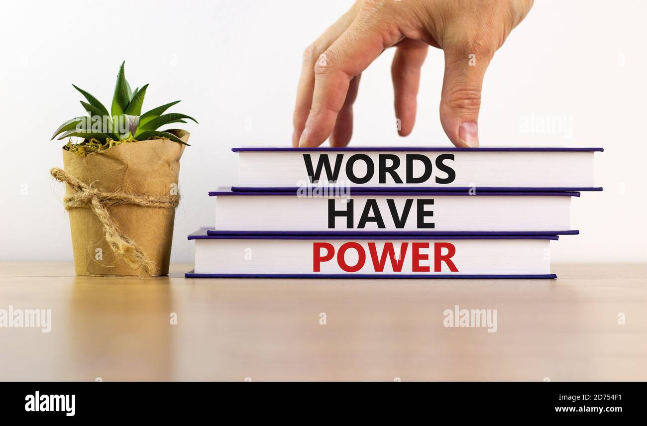 Books with text 'words have power' on beautiful wooden table. Male hand ...
