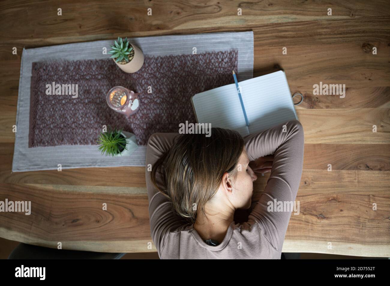 Top view of a tired young woman, student, sleeping on an open notebook ...