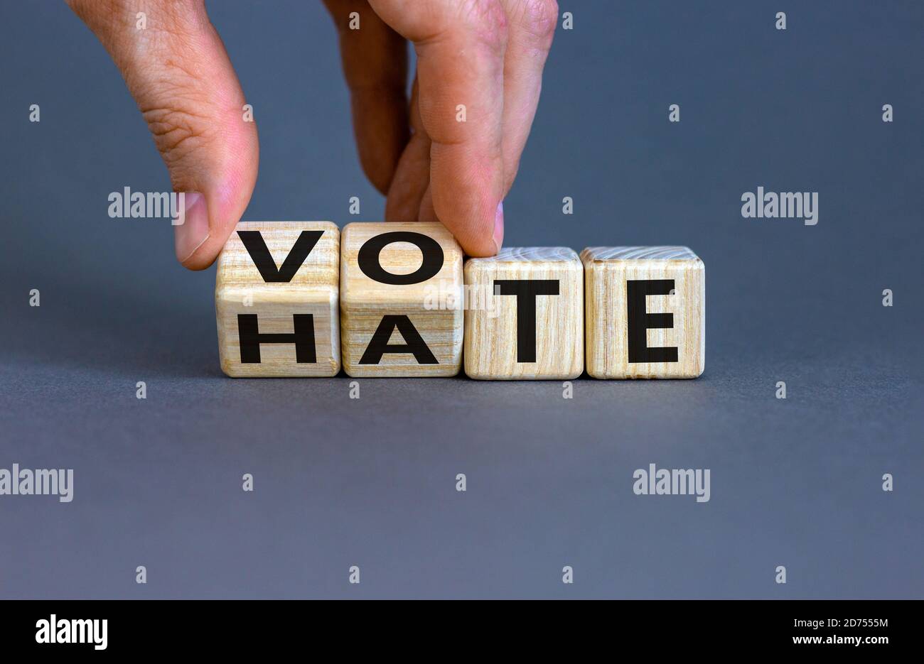 Hand turns wood cubes and change the words 'vote' to 'hate' or vice ...
