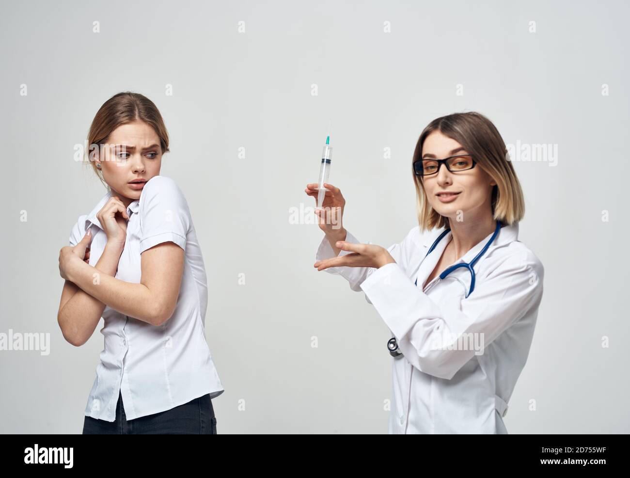 Frightened patient and nurse with a syringe in hand on a light ...
