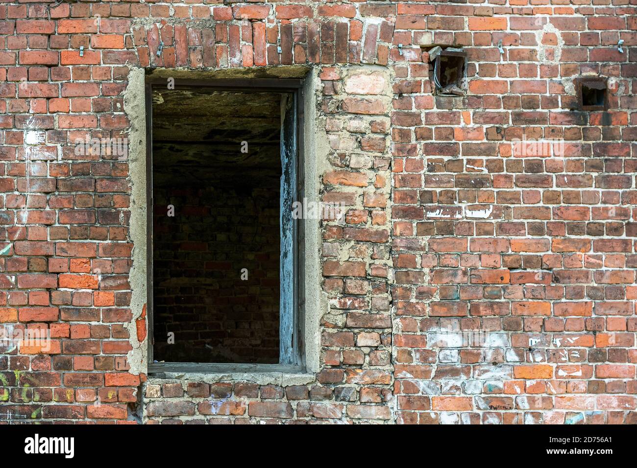 Destroyed window opening on a red brick wall in an old abandoned house ...