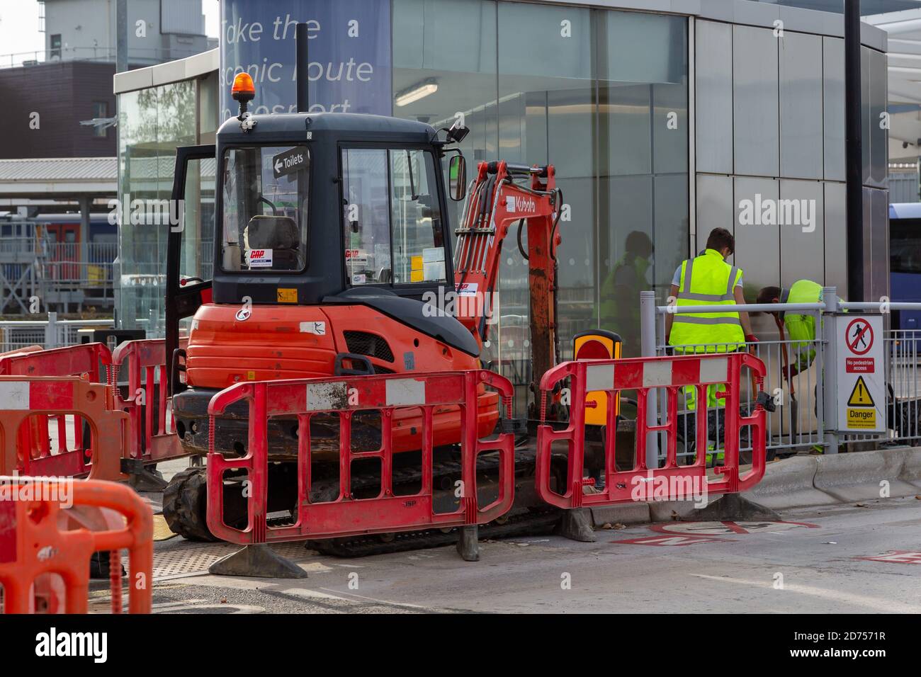 ground worker or builders working on a pavement next to a digger ...