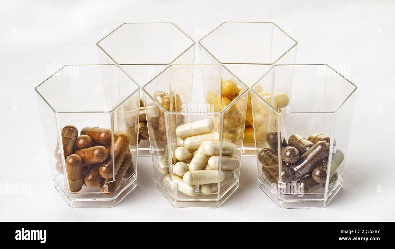 Various medical capsules and tablets in hexagonal transparent jars ...