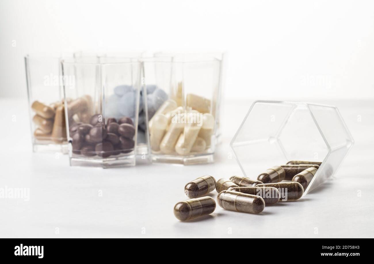 Medical capsules spilled out of a glass hexagonal jar Stock Photo - Alamy