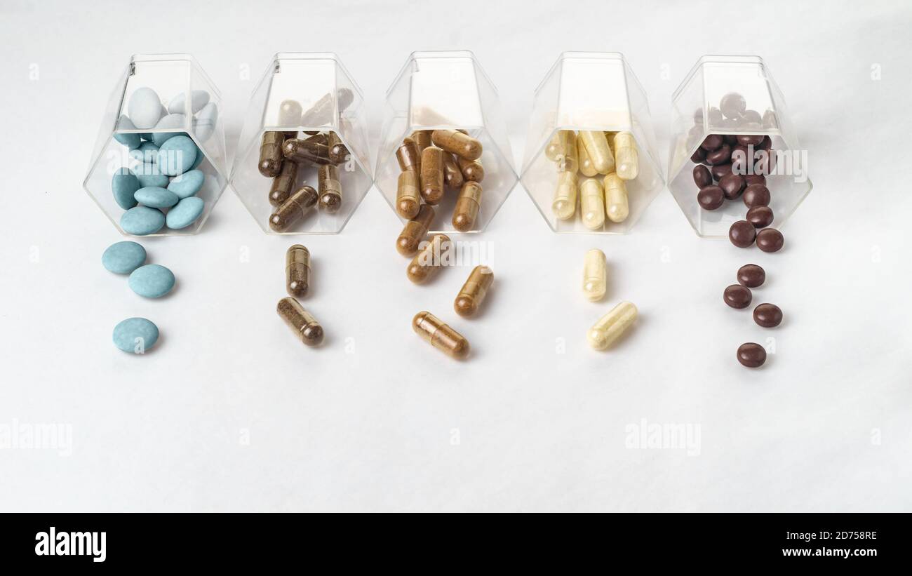 Variety of medical capsules and tablets spilled out of a glass ...