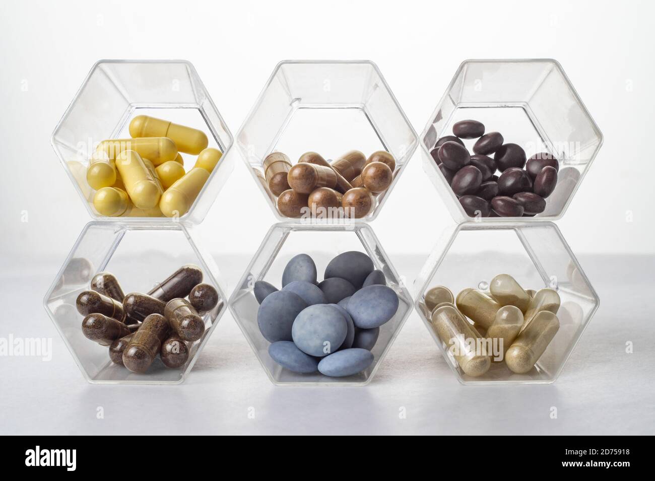 Various medical capsules and tablets in hexagonal transparent jars ...