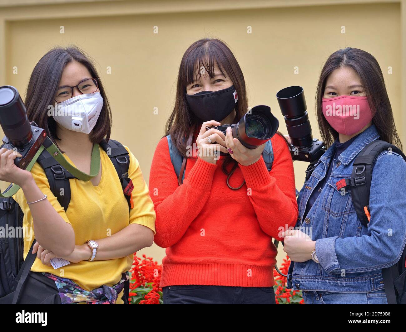 Three female Vietnamese street photographers wear protective face masks ...