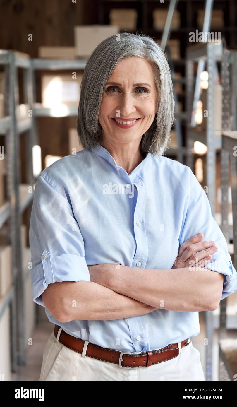 Smiling older woman manager standing in delivery shipping warehouse ...