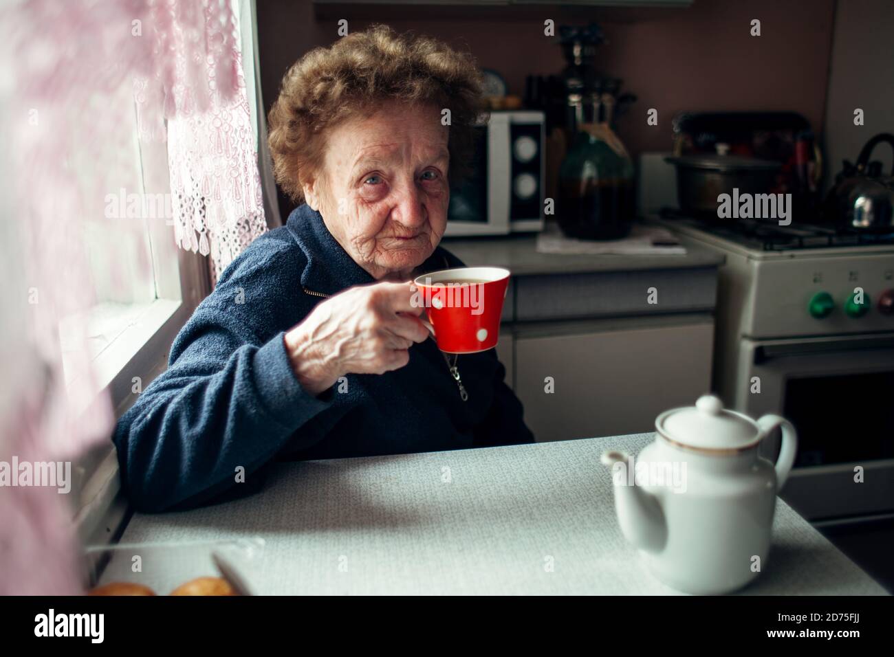 The old woman drinking tea in the kitchen at her rural home Stock Photo ...