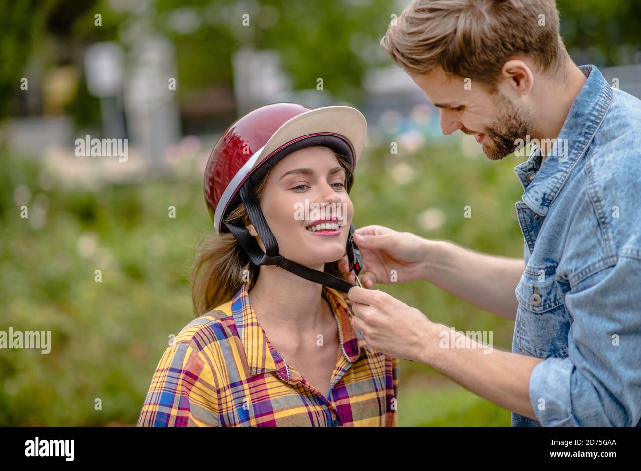 Man fixing a helmet on womans head Stock Photo - Alamy