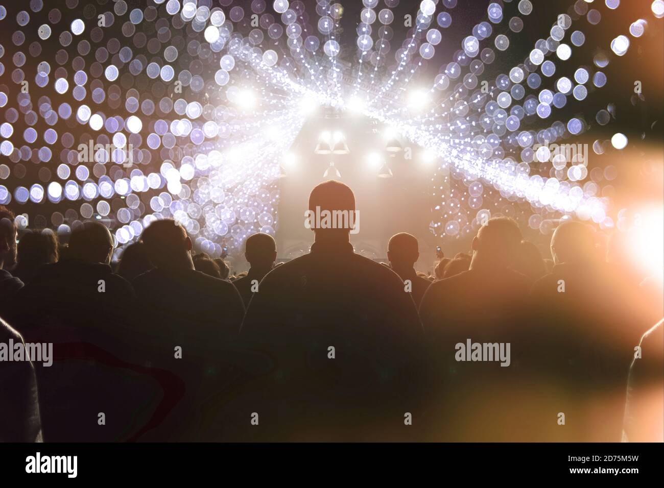 Large assembly of people in front of a large stage lit in the dark ...