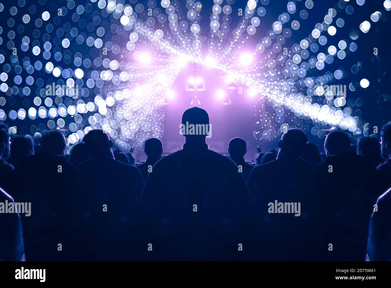 Large assembly of people in front of a large stage lit in the dark ...