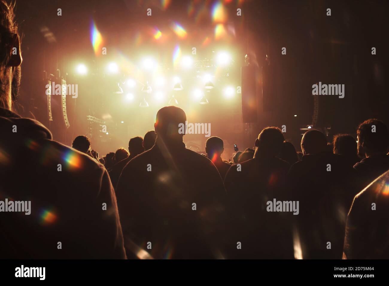 Large assembly of people in front of a large stage lit in the dark ...