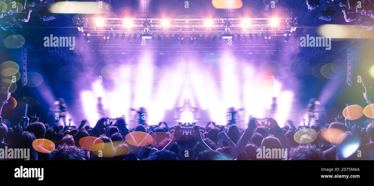Large assembly of people in front of a large stage lit in the dark ...