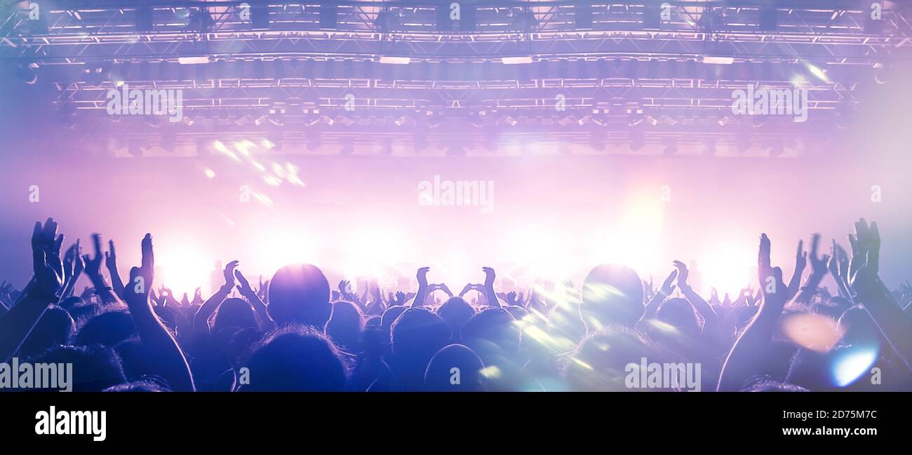 Large assembly of people in front of a large stage lit in the dark ...