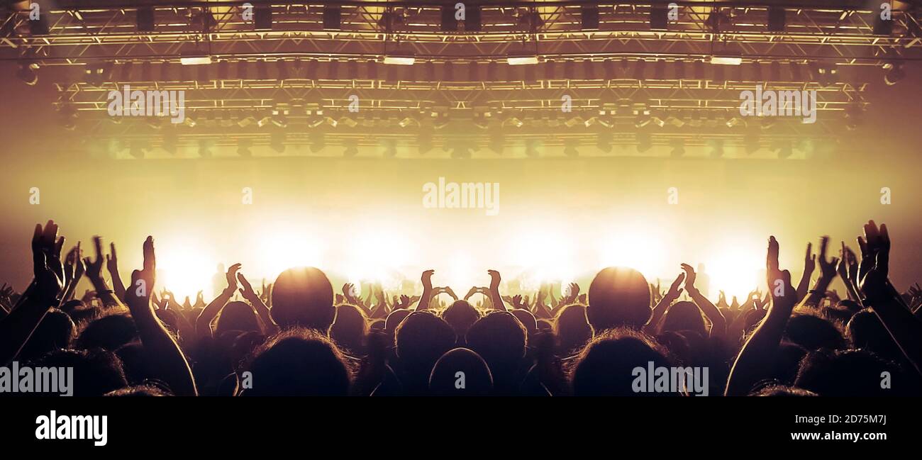 Large assembly of people in front of a large stage lit in the dark ...