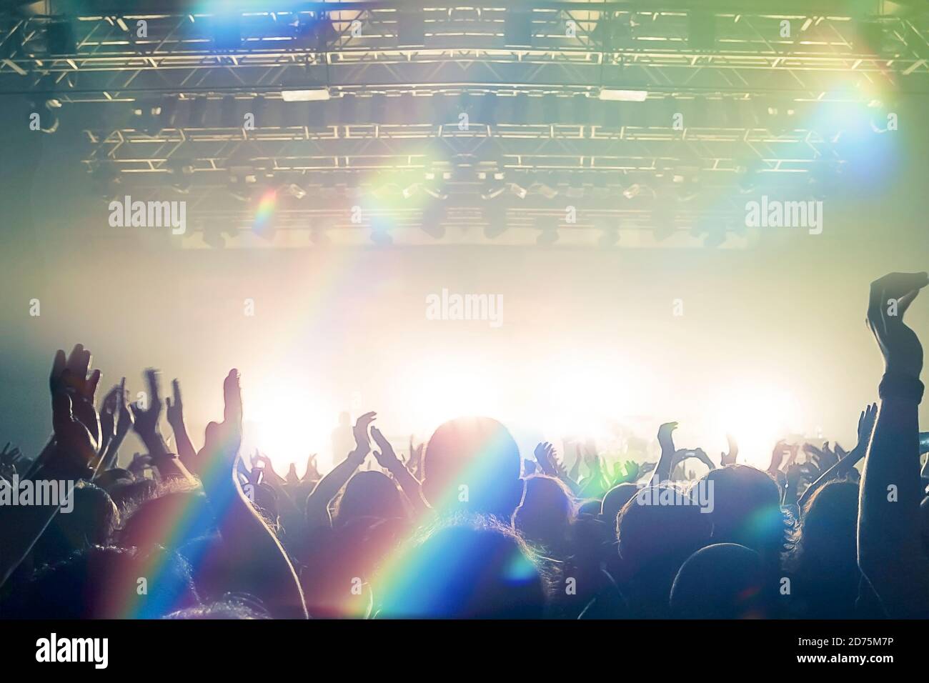 Large assembly of people in front of a large stage lit in the dark ...
